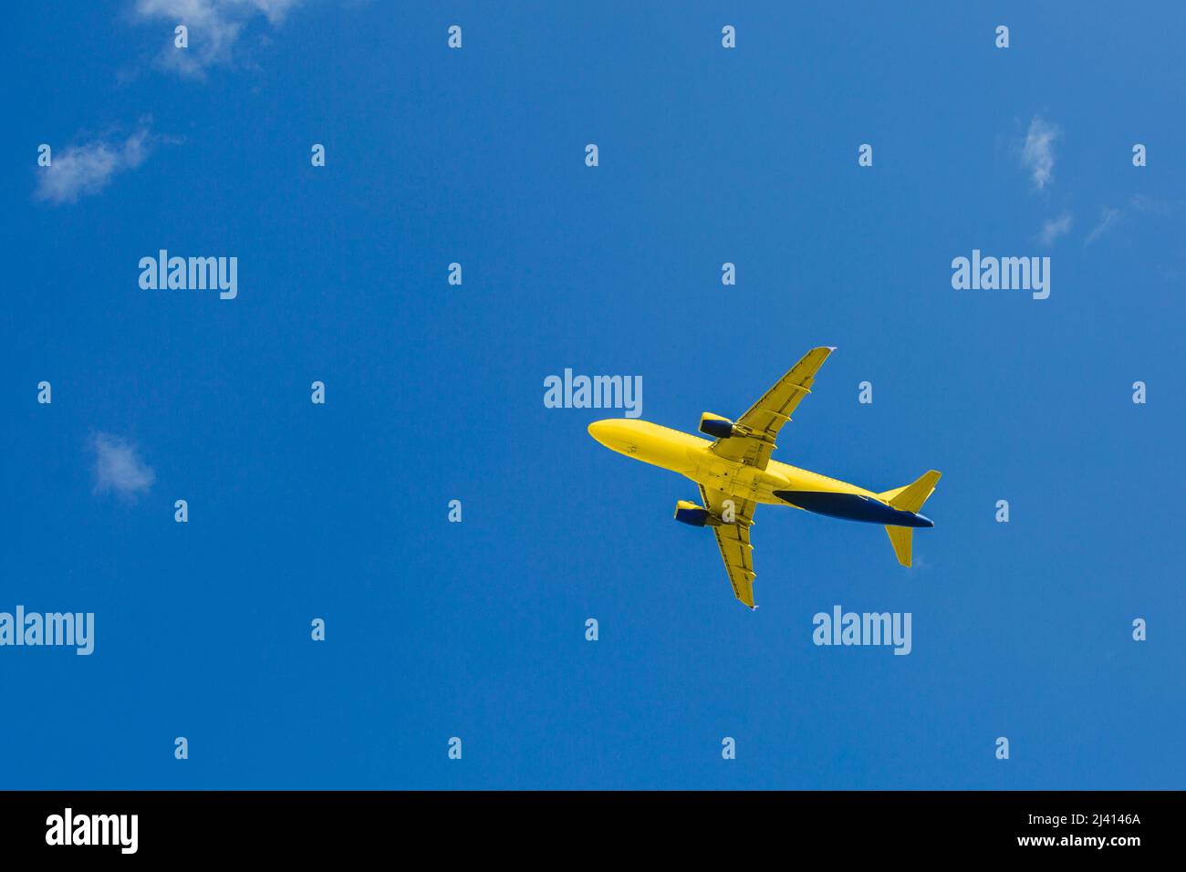 Yellow-blue passenger plane flies in the blue sky, air transportation ...
