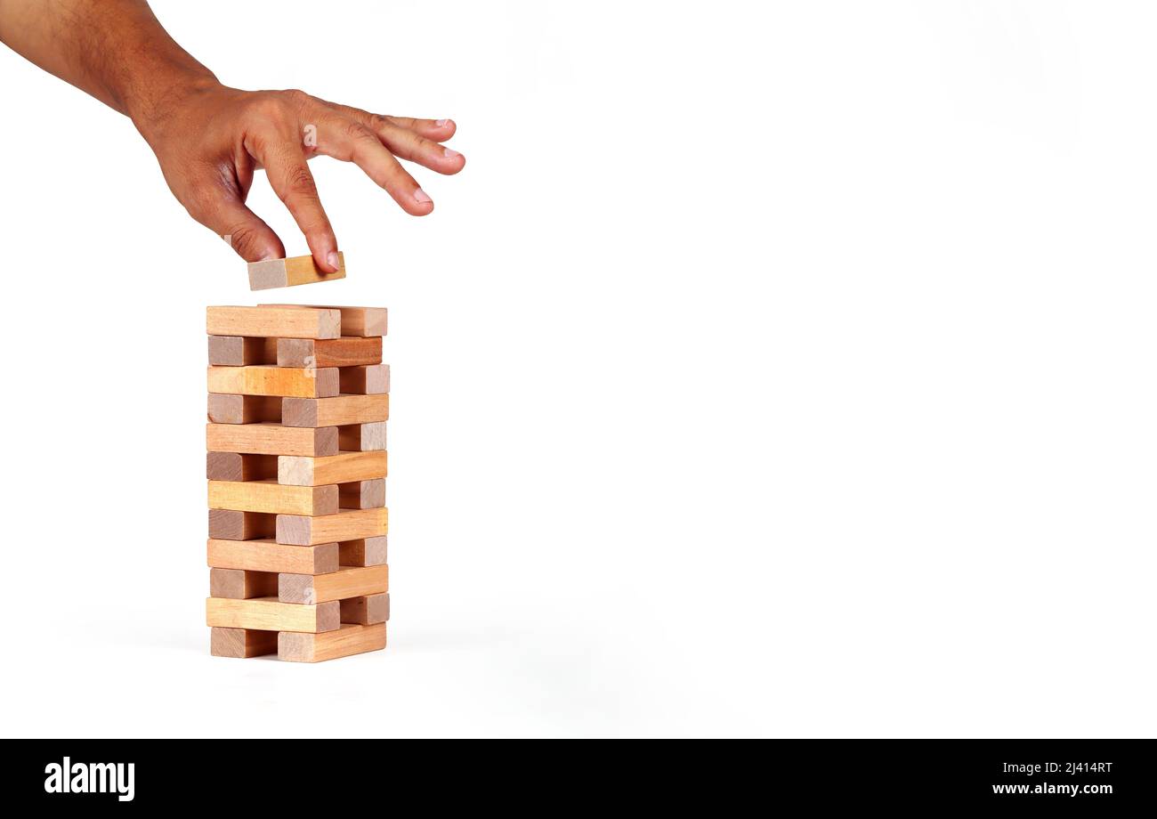 Man's hand put one block to the tower stack from wooden blocks toy with ...