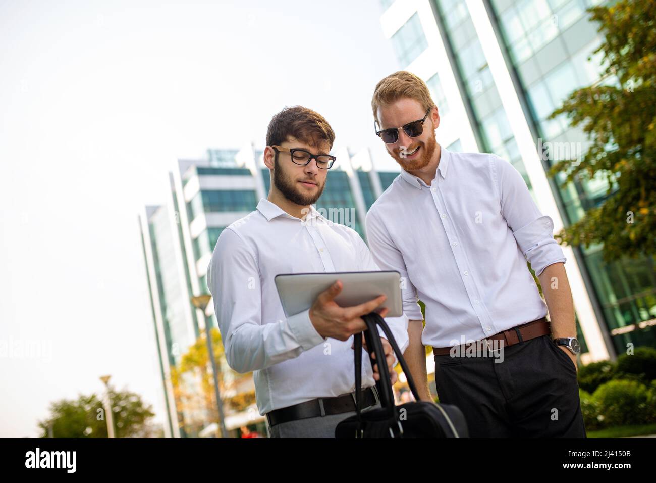 Two successful business men walking outdoors. Business, friendship ...