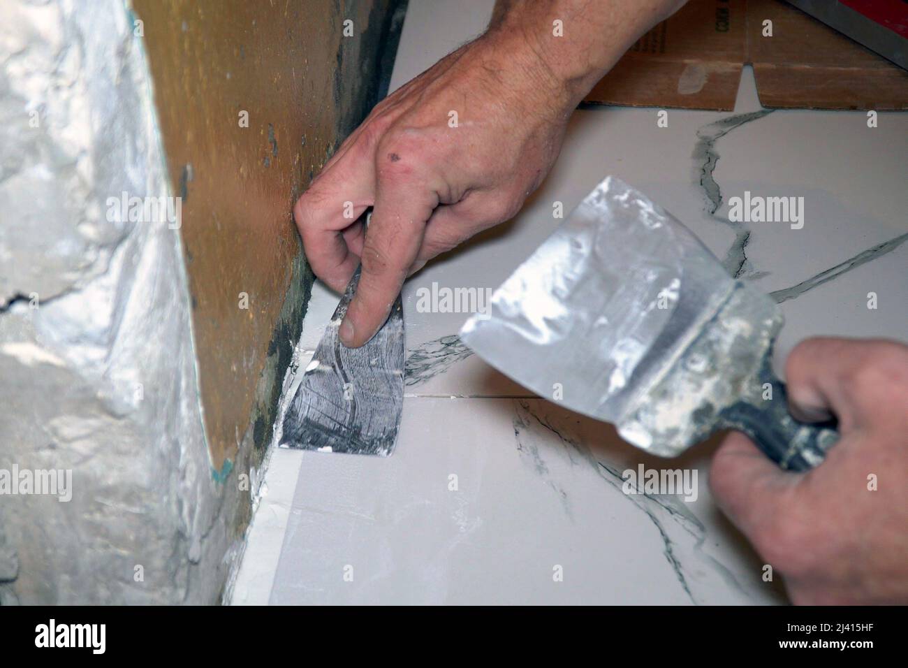 A worker puts a spatula on the floor when laying ceramic floor tiles ...