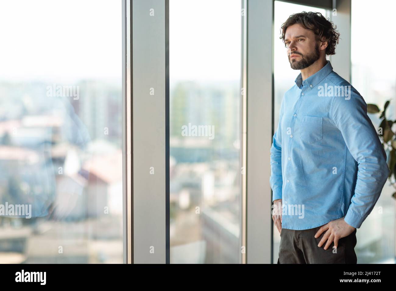 Portrait of confident business man looking through window Stock Photo ...