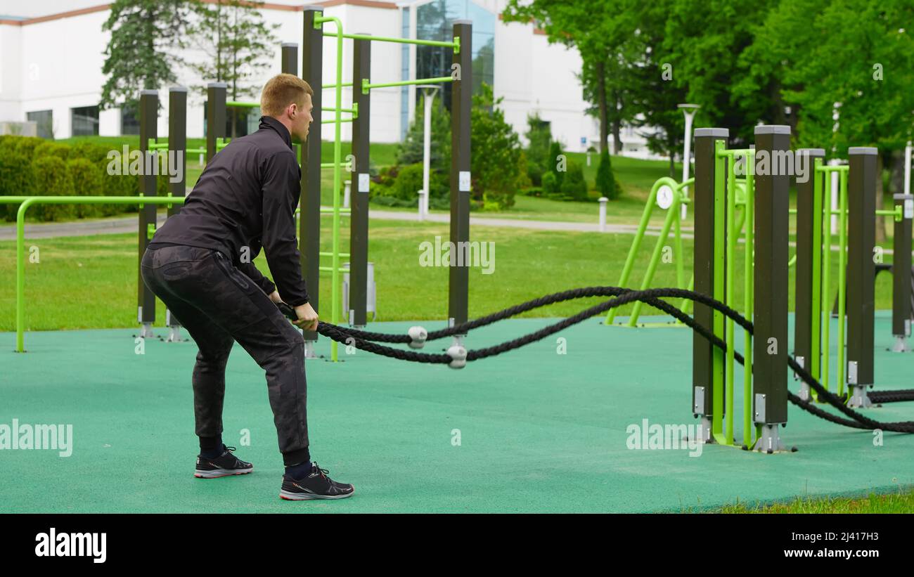 Men with battle rope battle ropes exercise in the street fitness gym ...