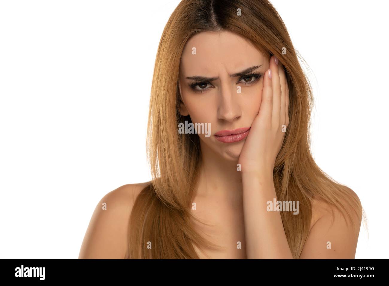 Portrait of a young blond woman with a toothache on a white background ...