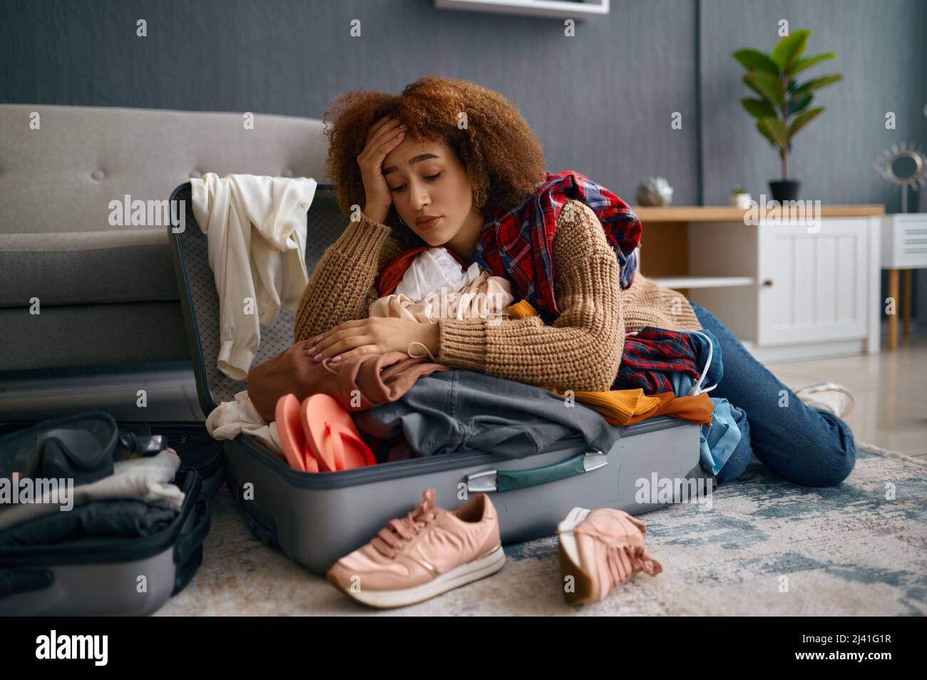 Sad young woman and unpacked vacation luggage Stock Photo - Alamy
