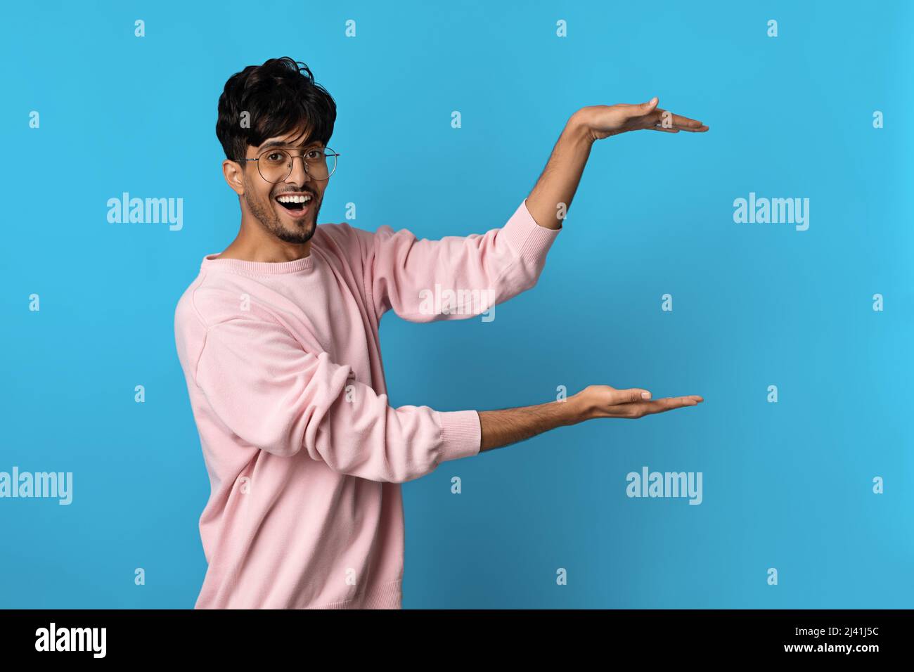 Positive hindu guy holding something invisible in his hands Stock Photo ...