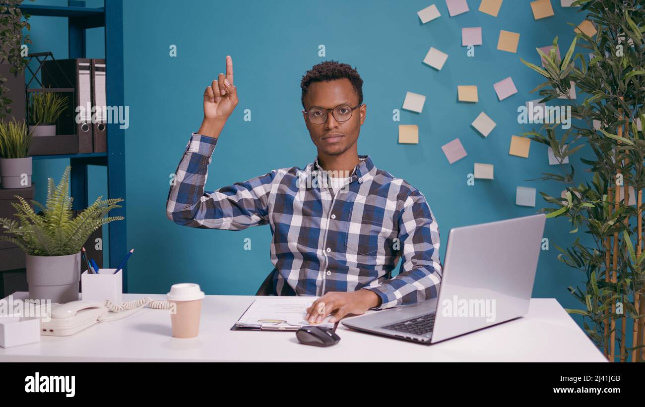 Serious person pointing up with index finger at office desk, indicating ...