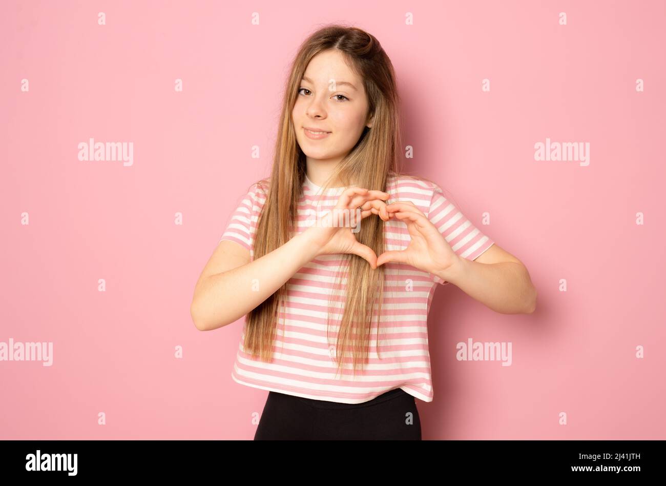 Attractive young caucasian girl feels happy and romantic shapes heart ...