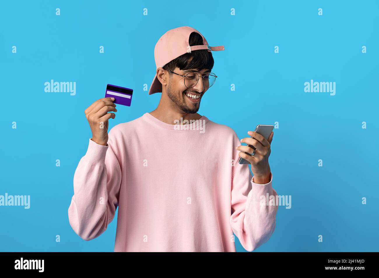 Cheerful indian guy holding cell phone and credit card Stock Photo - Alamy