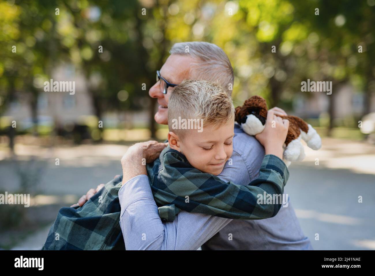 Happy little boy hugging his grandfather outdoors in park Stock Photo ...