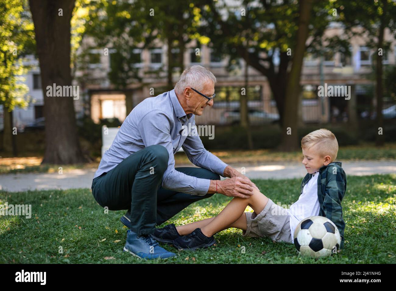 Little boy with injured leg getting plaster from grandfather outdoors ...