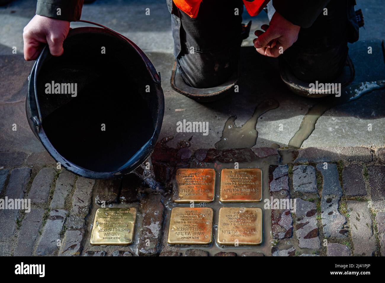 A man is seen cleaning the stumbling stones after just being placed. As ...