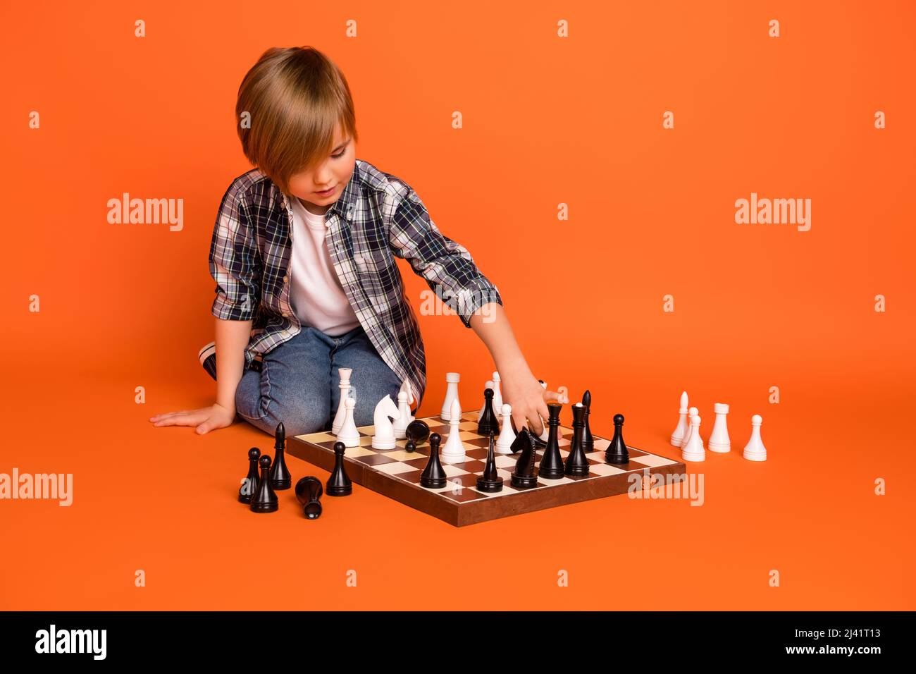 Full body photo of young boy sit floor play game clever learn chess ...