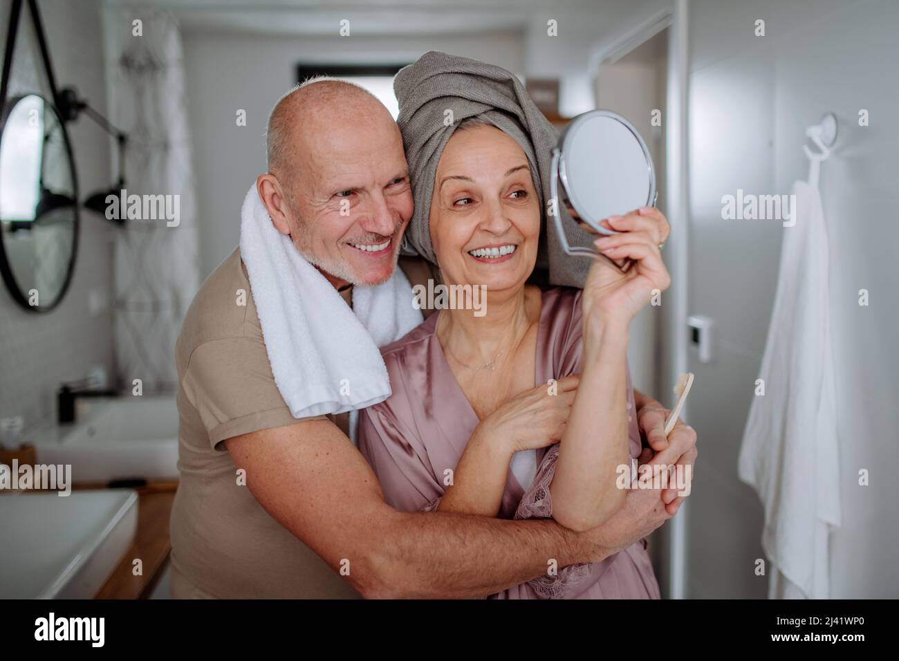 Senior couple in love in bathroom, looking at mirror and smiling ...