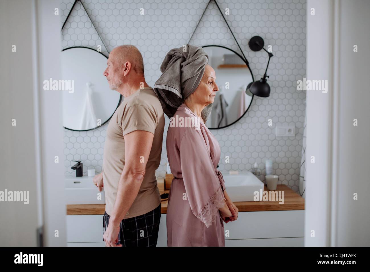 Senior couple in bathroom, standing back to back, relationship problems ...