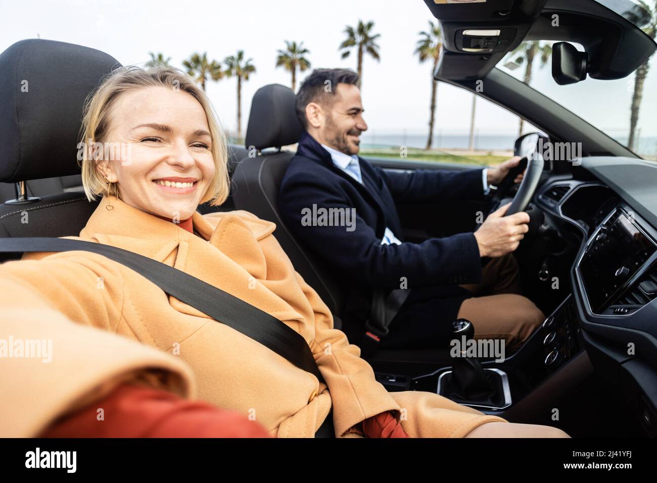Smiling mid adult couple driving a car on road trip at the beach Stock ...
