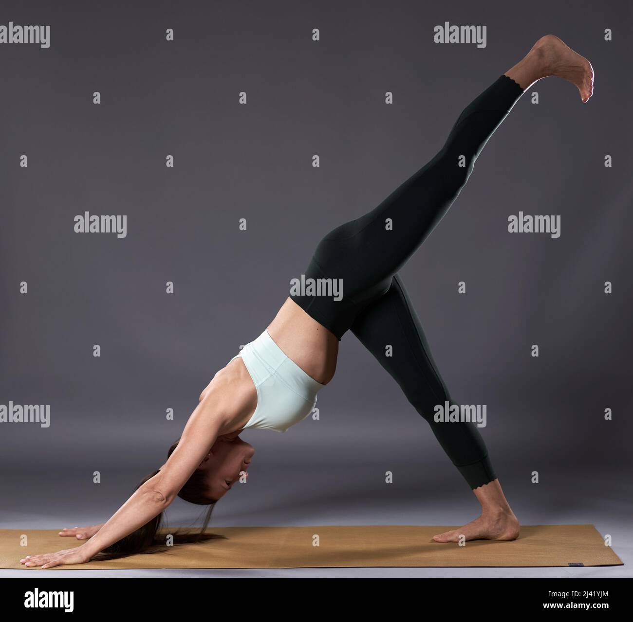 Woman yoga trainer in a variation of Adho Mukha Svanasana (downward ...