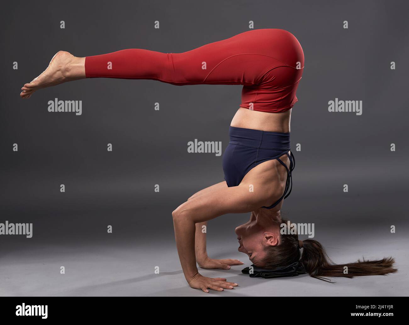 Woman Yoga practitioner doing Sirsasana (head stand) pose Stock Photo ...