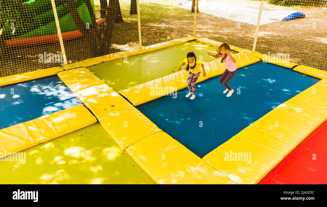 Little pretty girls having fun outdoor. Jumping on trampoline in ...