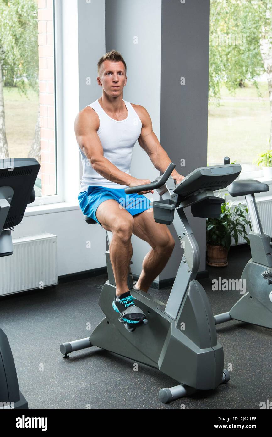 Young muscular man on exercise bike in gym Stock Photo - Alamy