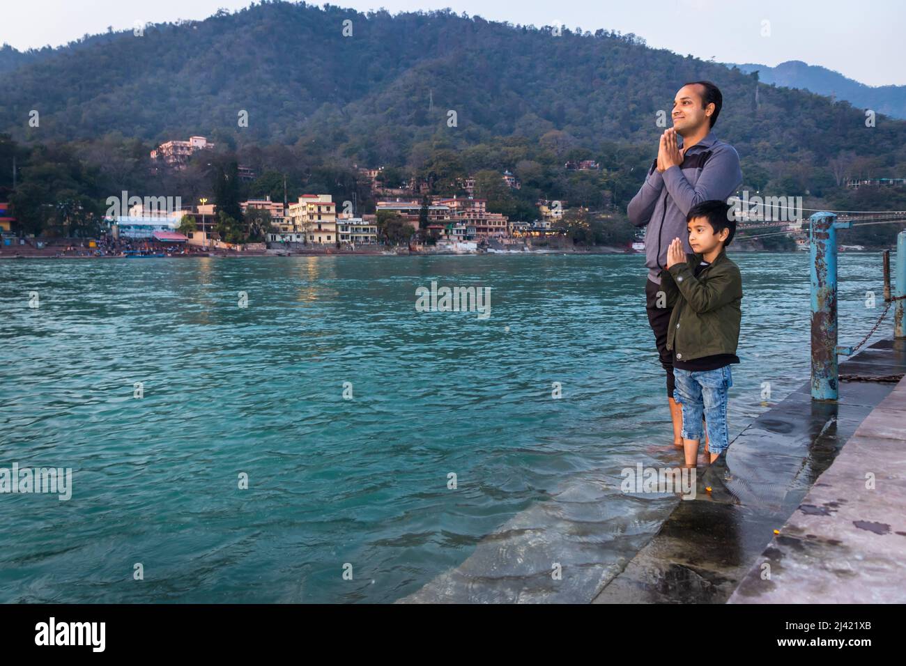 isolated young man and kid prying the holy ganges river at river bank ...