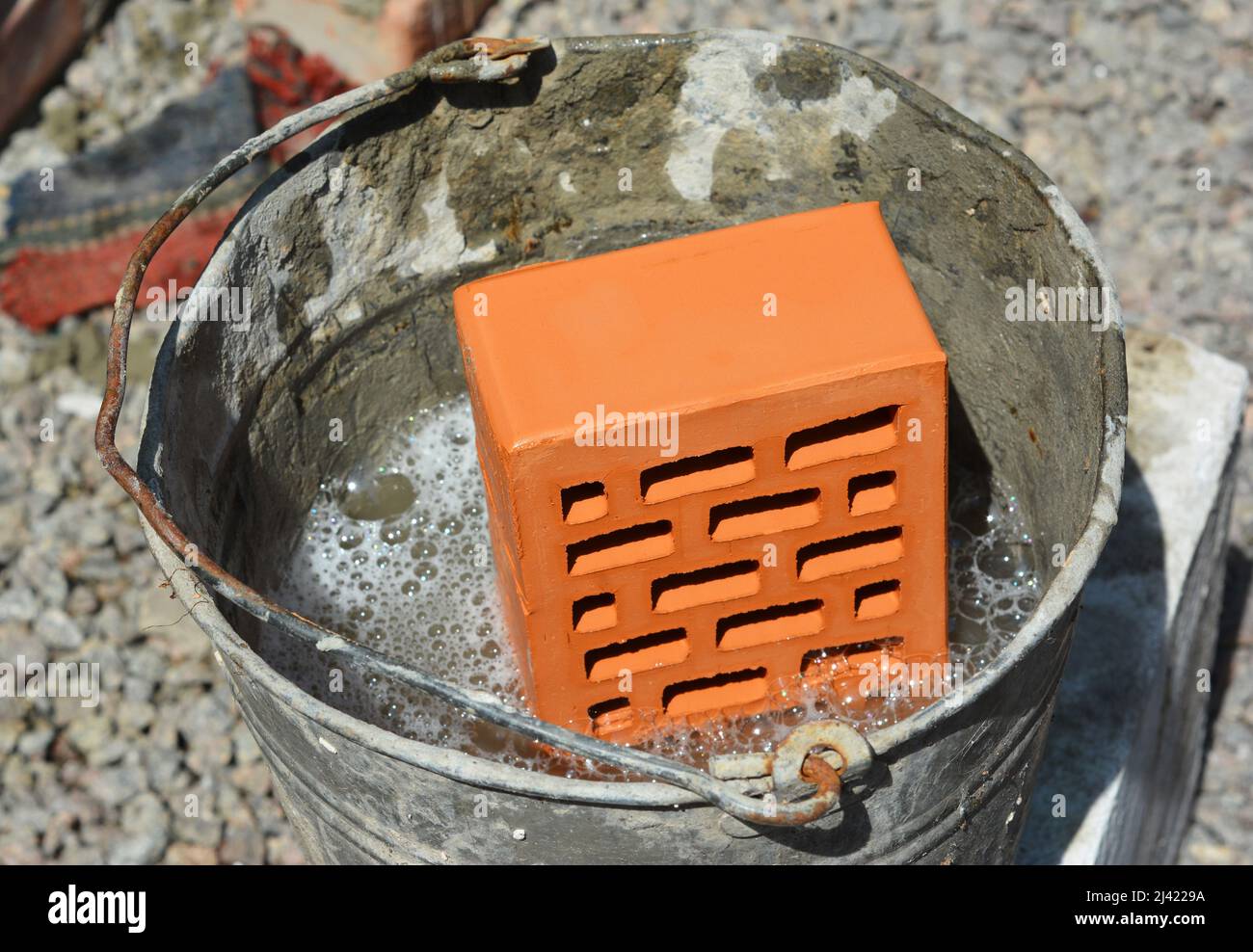 Bricklaying and brickwork. Soaking bricks in a bucket with water before ...