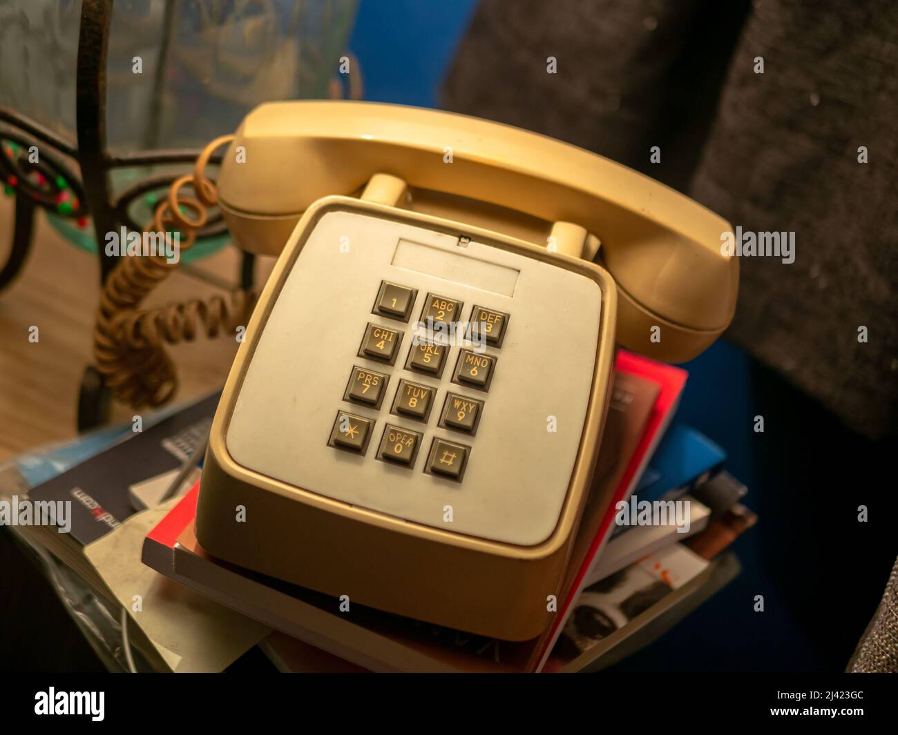 Old telephone with a cream keyboard on a table on top of some books ...