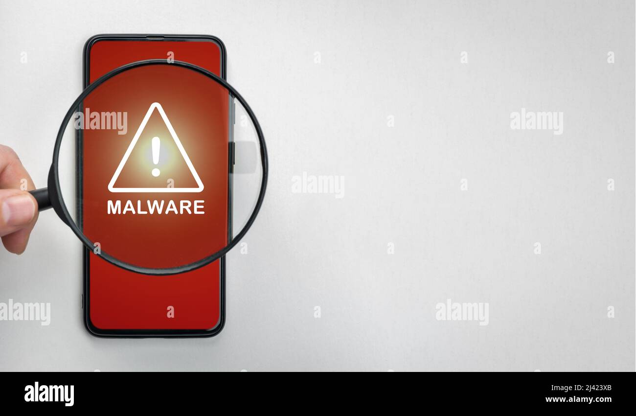 Magnifying glass on cell phone, an alarm sign detecting malware. Mobile ...