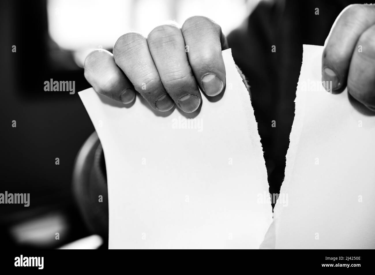 Two hands tearing a single blank sheet of paper from top to bottom ...