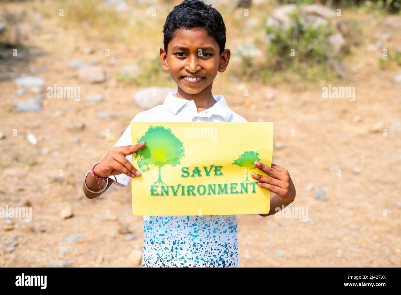 Smiling teenger boy holding save environment sign board by looking at ...