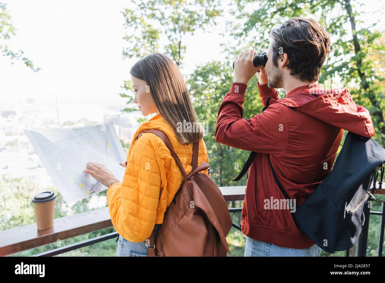 Side view of young woman looking at map near coffee to go and boyfriend ...