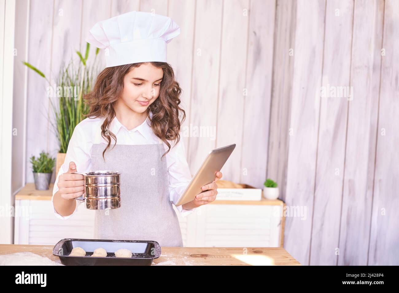 Young girl cooking at kitchen. Curly pretty child portrait. Chef ...
