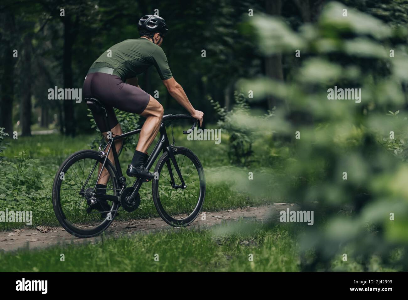 Back view of muscular man using professional black bike for cycling on ...