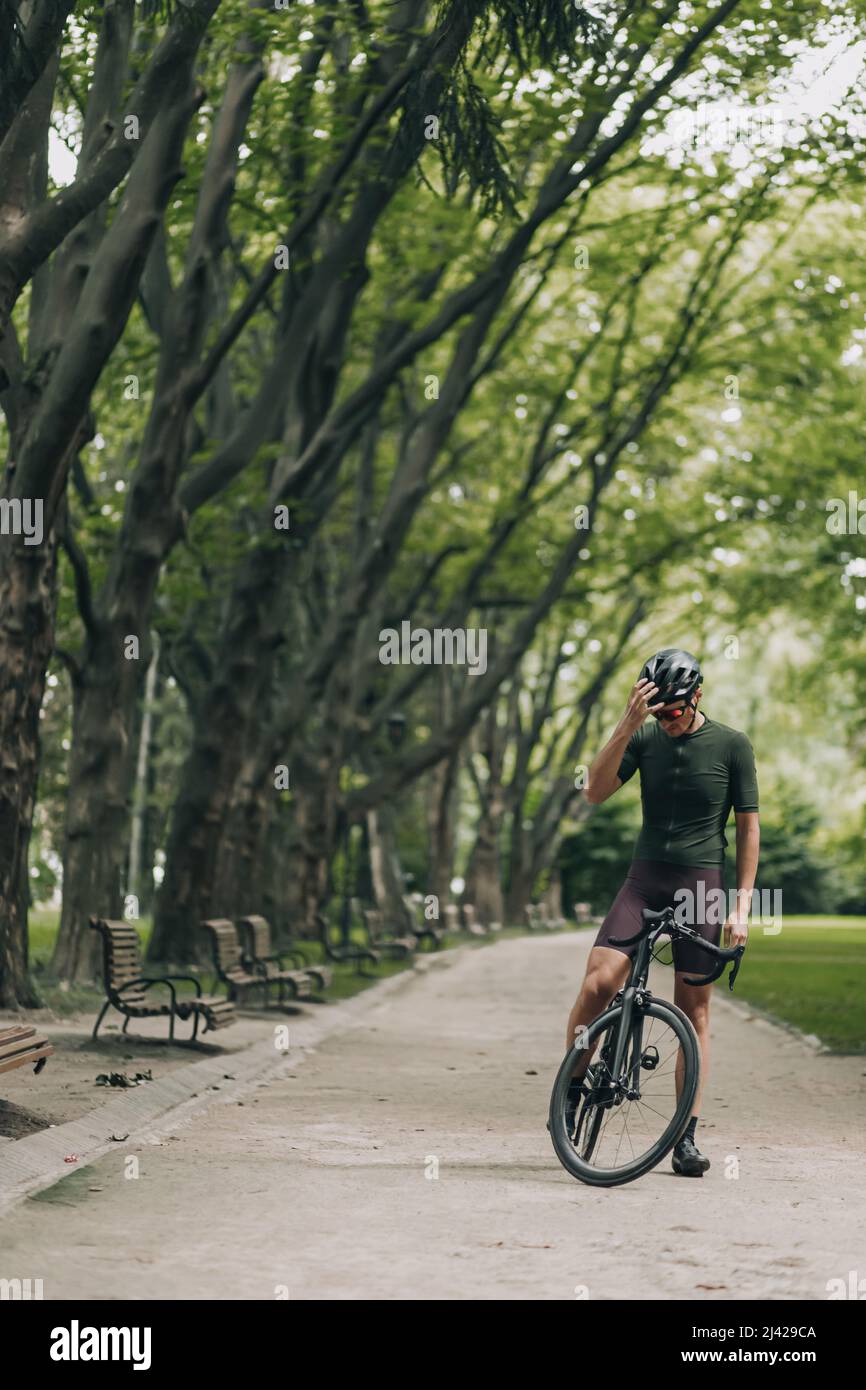 Young cyclist with muscular legs posing at green city park with ...