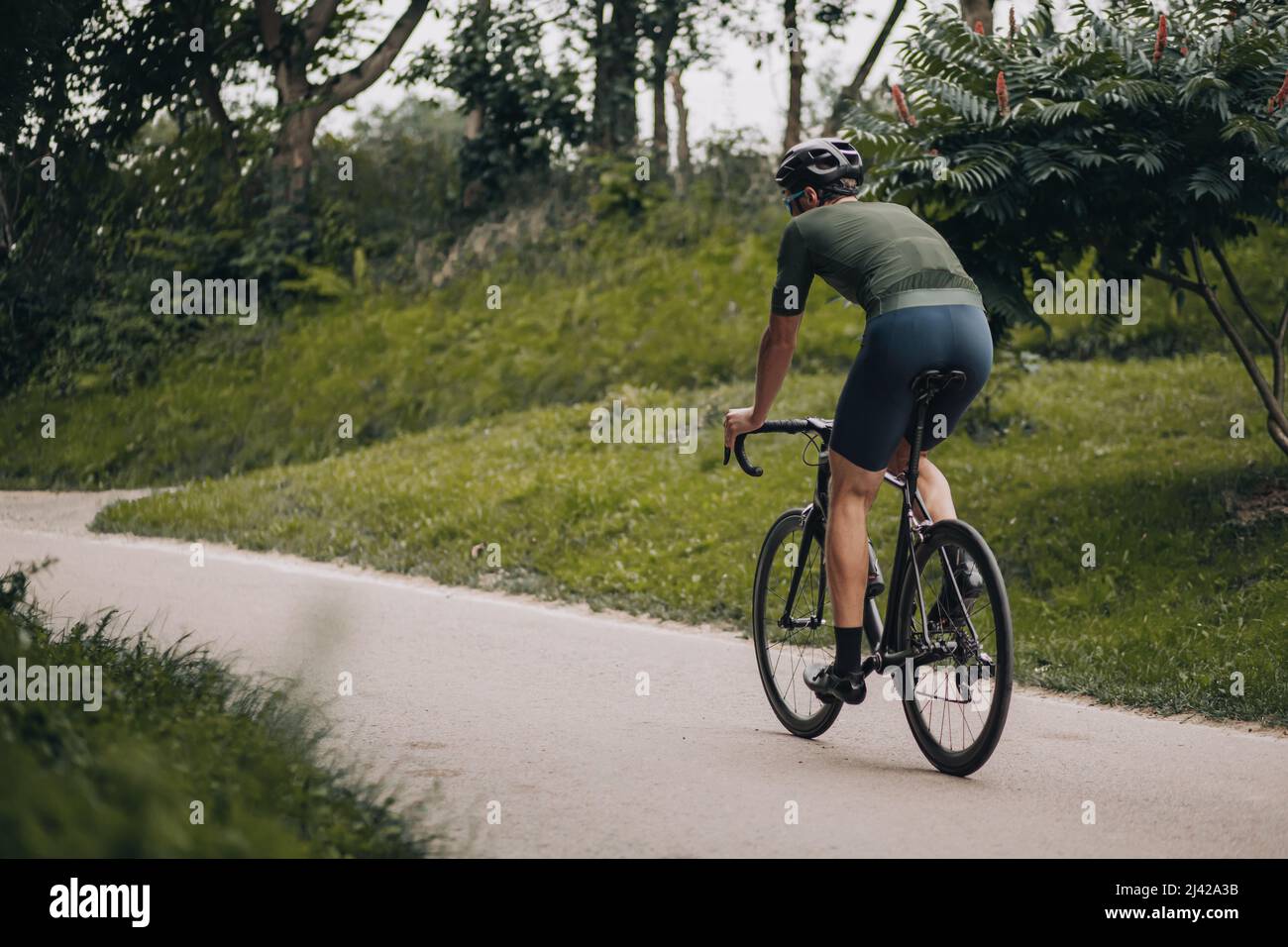Back view of muscular man in sport outfit and protective helmet cycling ...