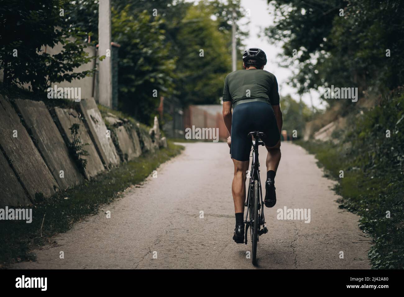Back view of muscular guy practising in cycling during morning time ...