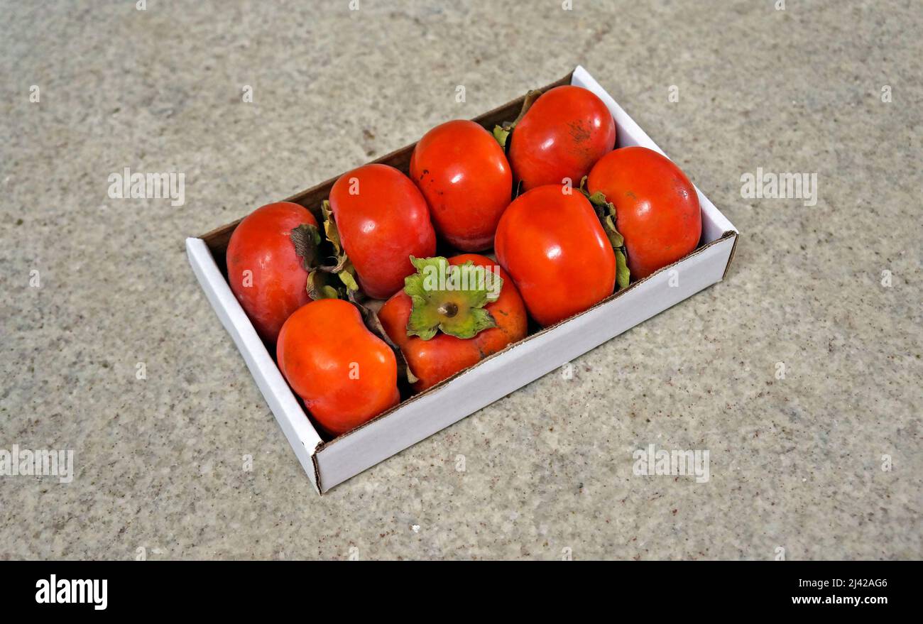 Persimmons in a carton box on granite background Stock Photo - Alamy