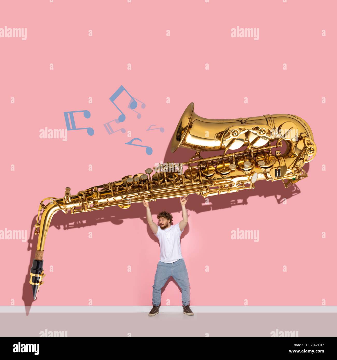 Creative design. Young man holding giant golden trumpet isolated over ...