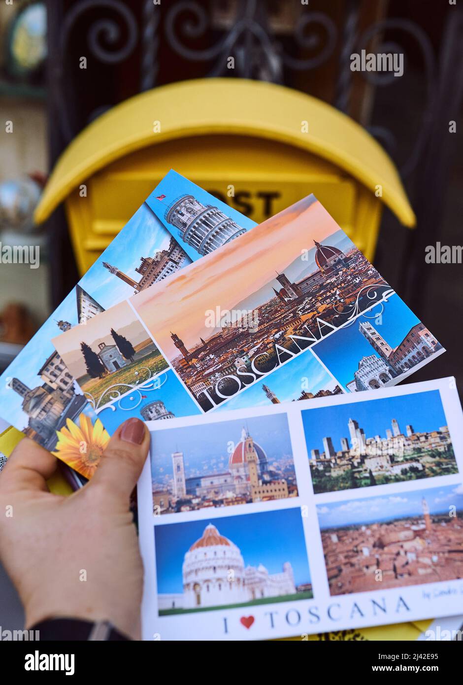 PISA, ITALY - OCTOBER 15, 2021: Hand holding postcards by the post box ...