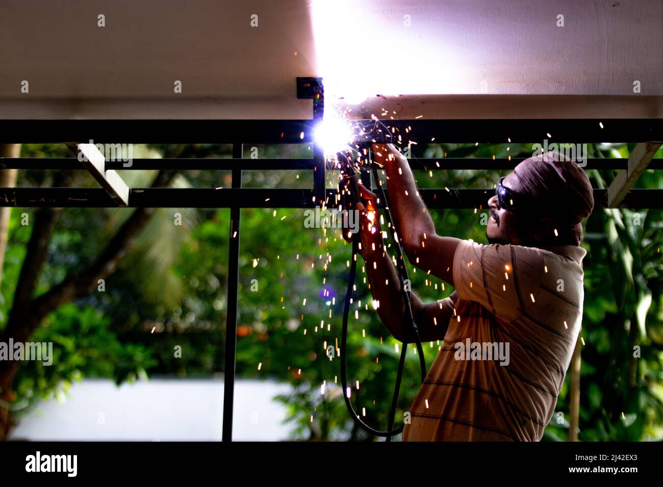 a man doing welding works on roof top Stock Photo - Alamy