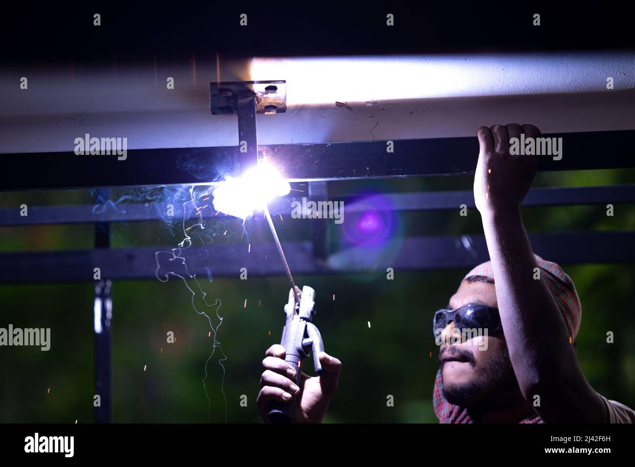 a man doing welding works on roof top Stock Photo - Alamy