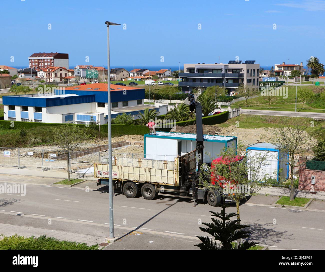Lorry mounted crane delivering a cabin orkmans hut to a building site ...