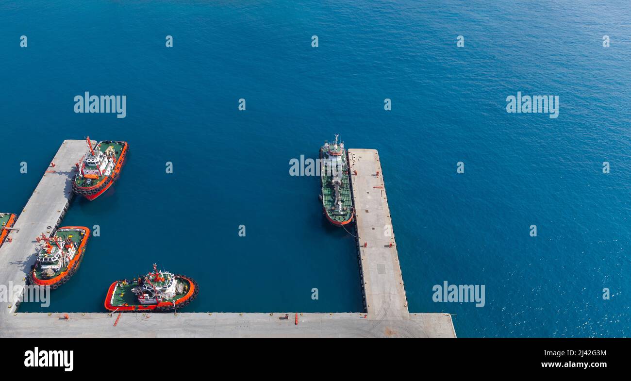 Tug boats and tanker vessel are moored in port. Aerial view. Jedda port ...