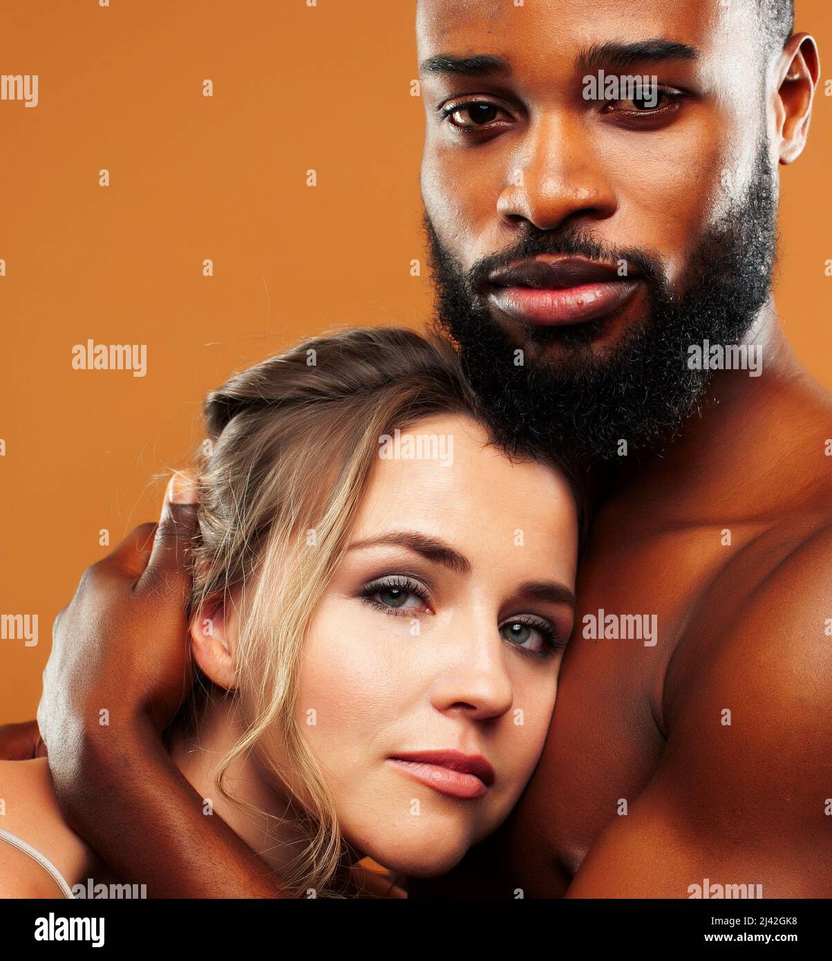Young pretty couple diverse races together posing sensitive on brown ...