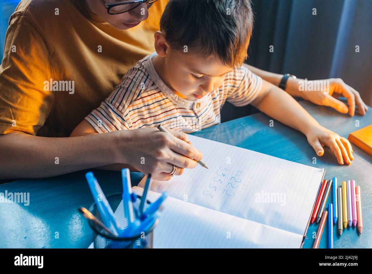 Mother teaching writing math number her son at home. Mom and boy hand ...