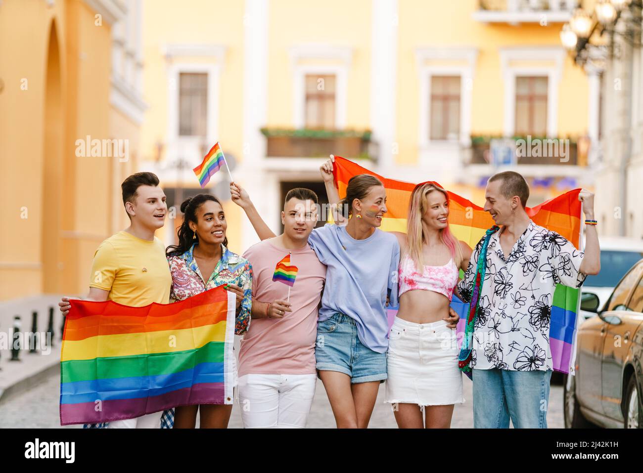 Multiracial men and women walking with rainbow flags during pride ...