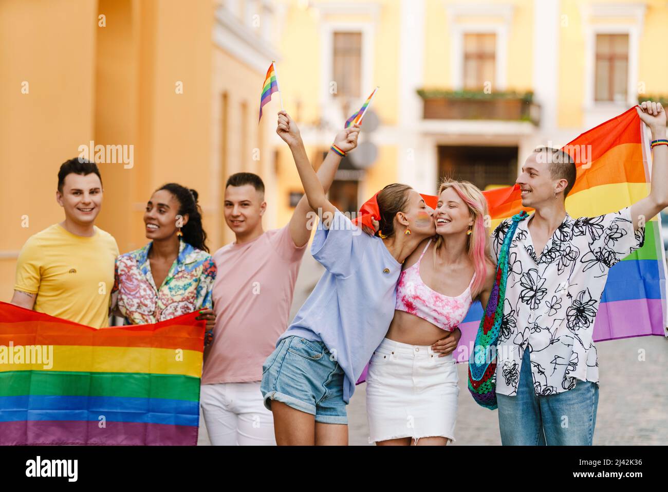 Multiracial men and women walking with rainbow flags during pride ...
