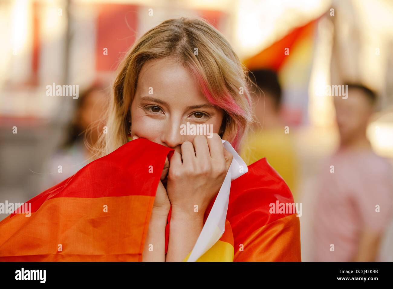 White woman holding rainbow flag during pride parade at city street ...