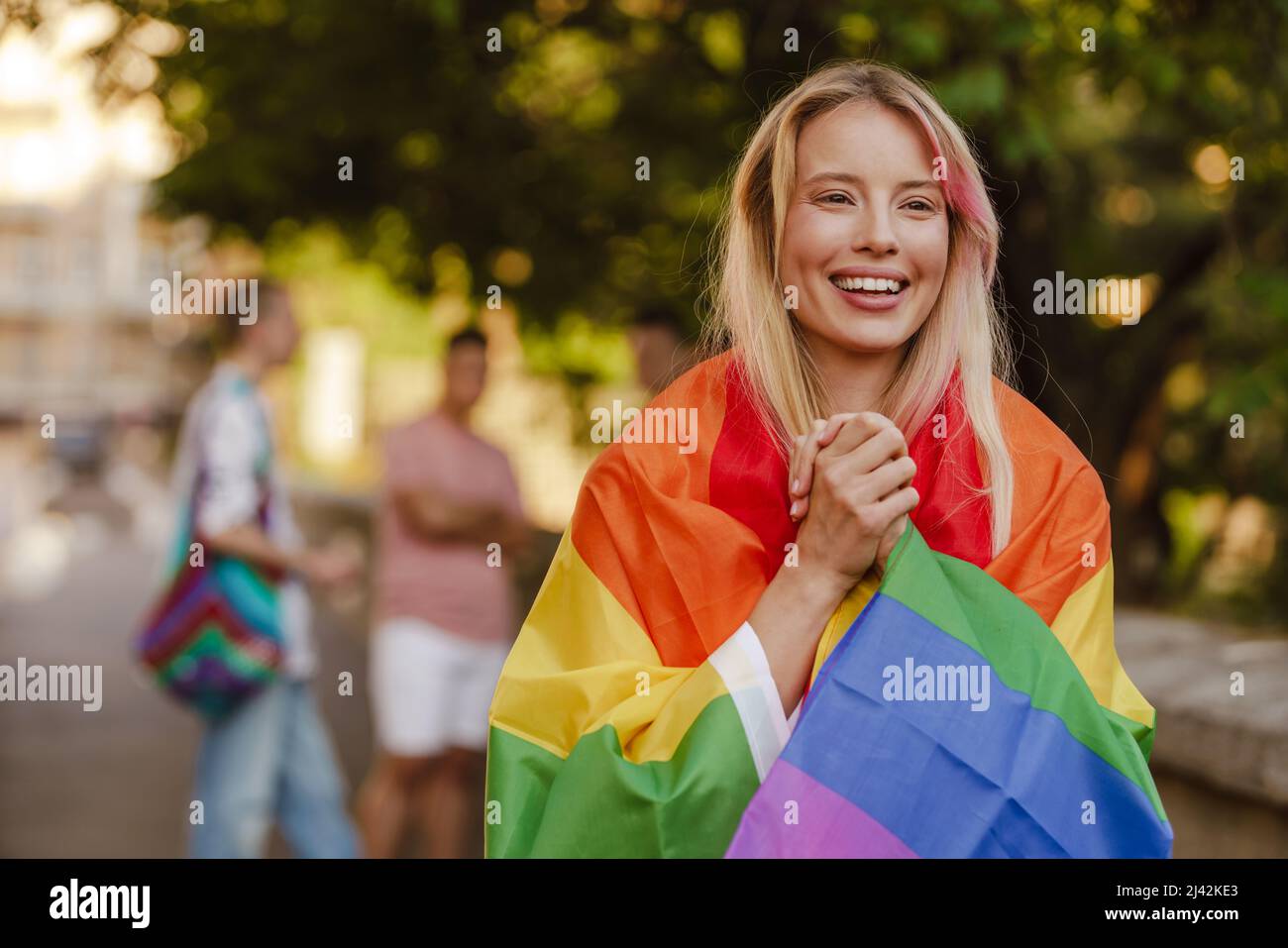 White woman laughing and holding rainbow flag during pride parade at ...