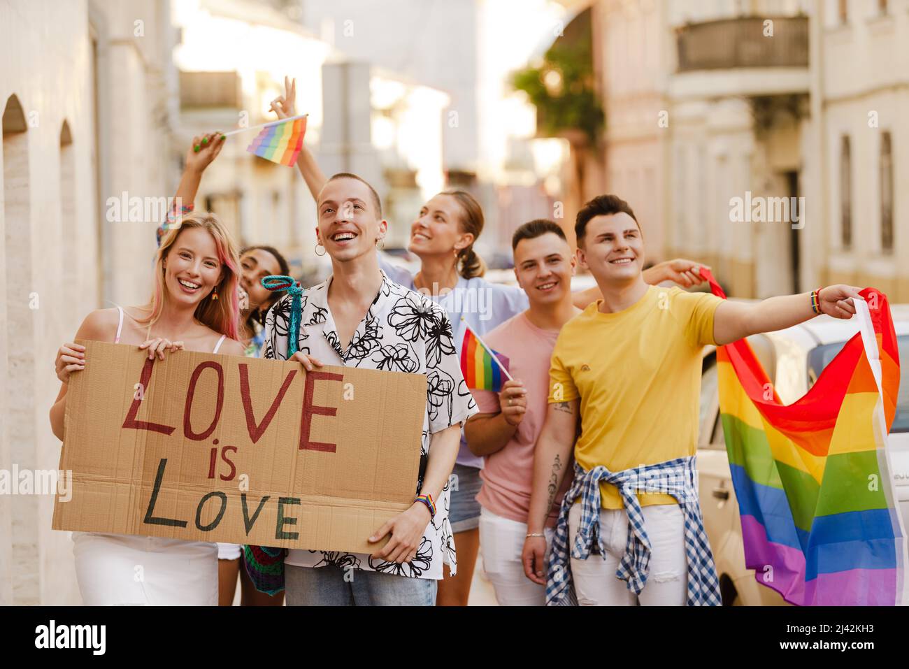 Men and women walking with rainbow flags and placard during pride ...