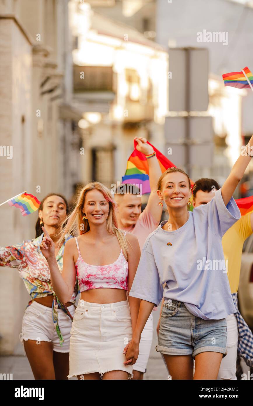 Multiracial men and women walking with rainbow flags during pride ...